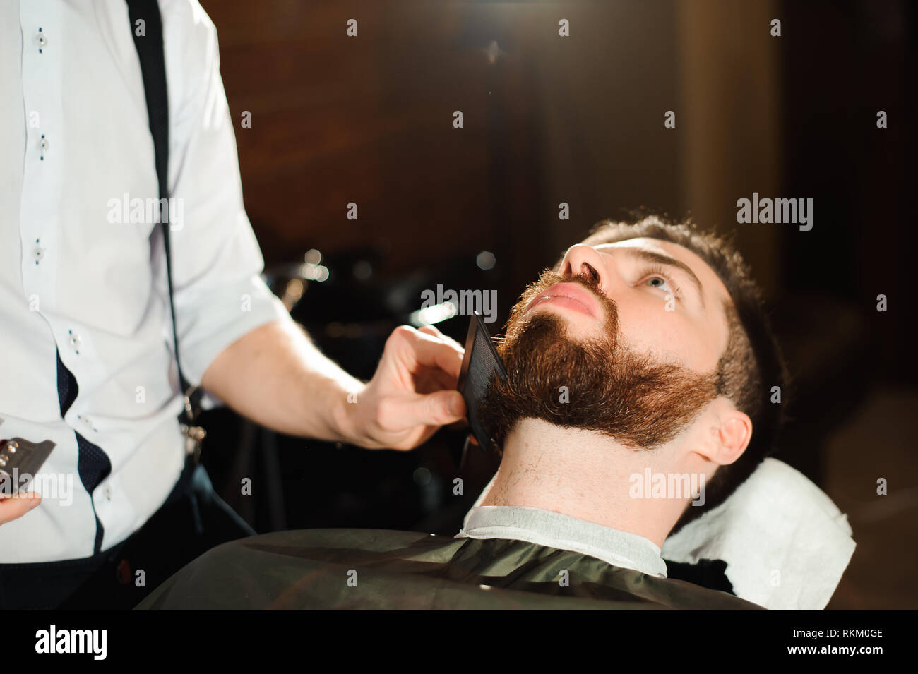 Master cuts hair and beard of men in the barbershop Stock Photo - Alamy