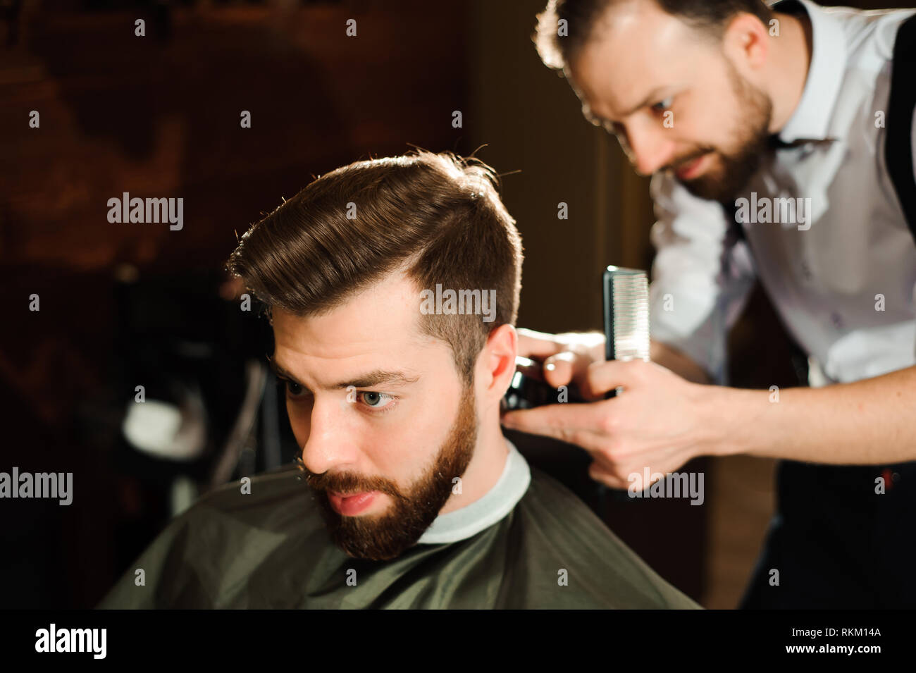 Master cuts hair and beard of men in the barbershop Stock Photo - Alamy