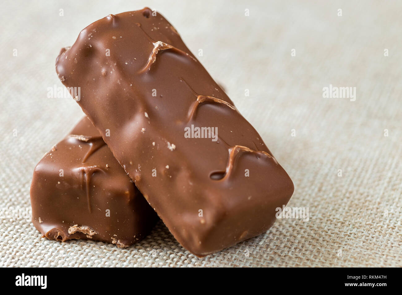 Two isolated isolated dark brown chocolate candy snickers bars on light ...
