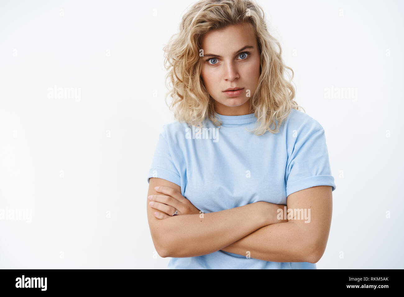 Girl Standing In Closed Defensive Pose With Hands Crossed Over Chest Looking Intense And Serious