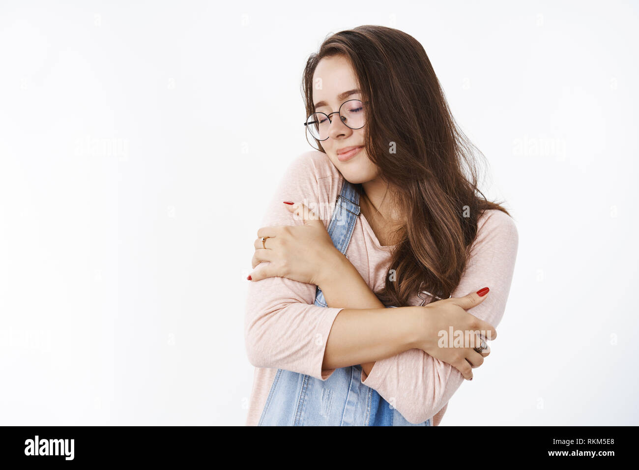 Waist-up shot of romantic dreamy good-looking female hugging herself ...
