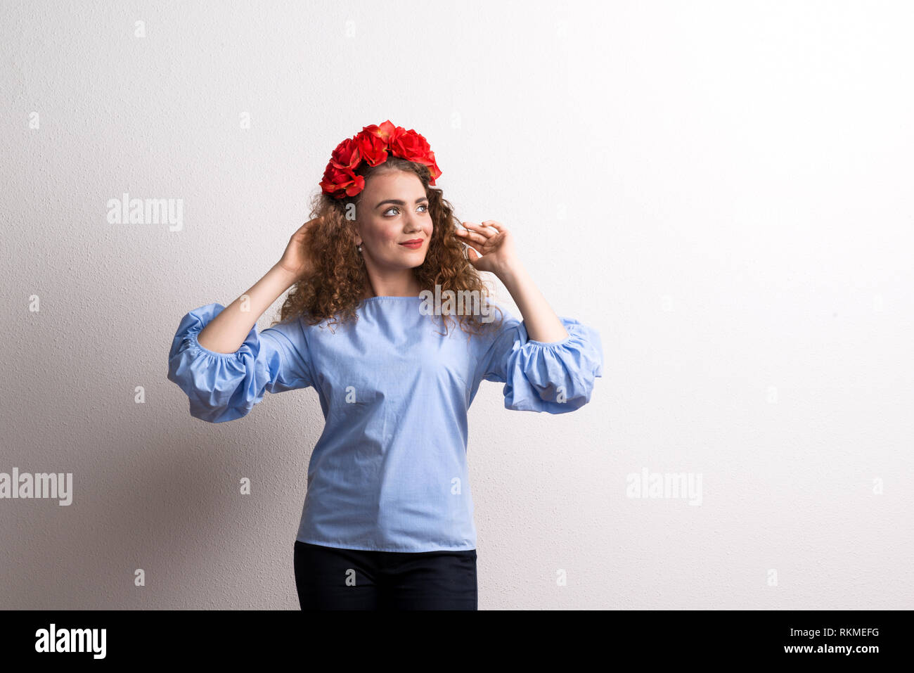 A front view of young beautiful woman with flower headband, hands ...
