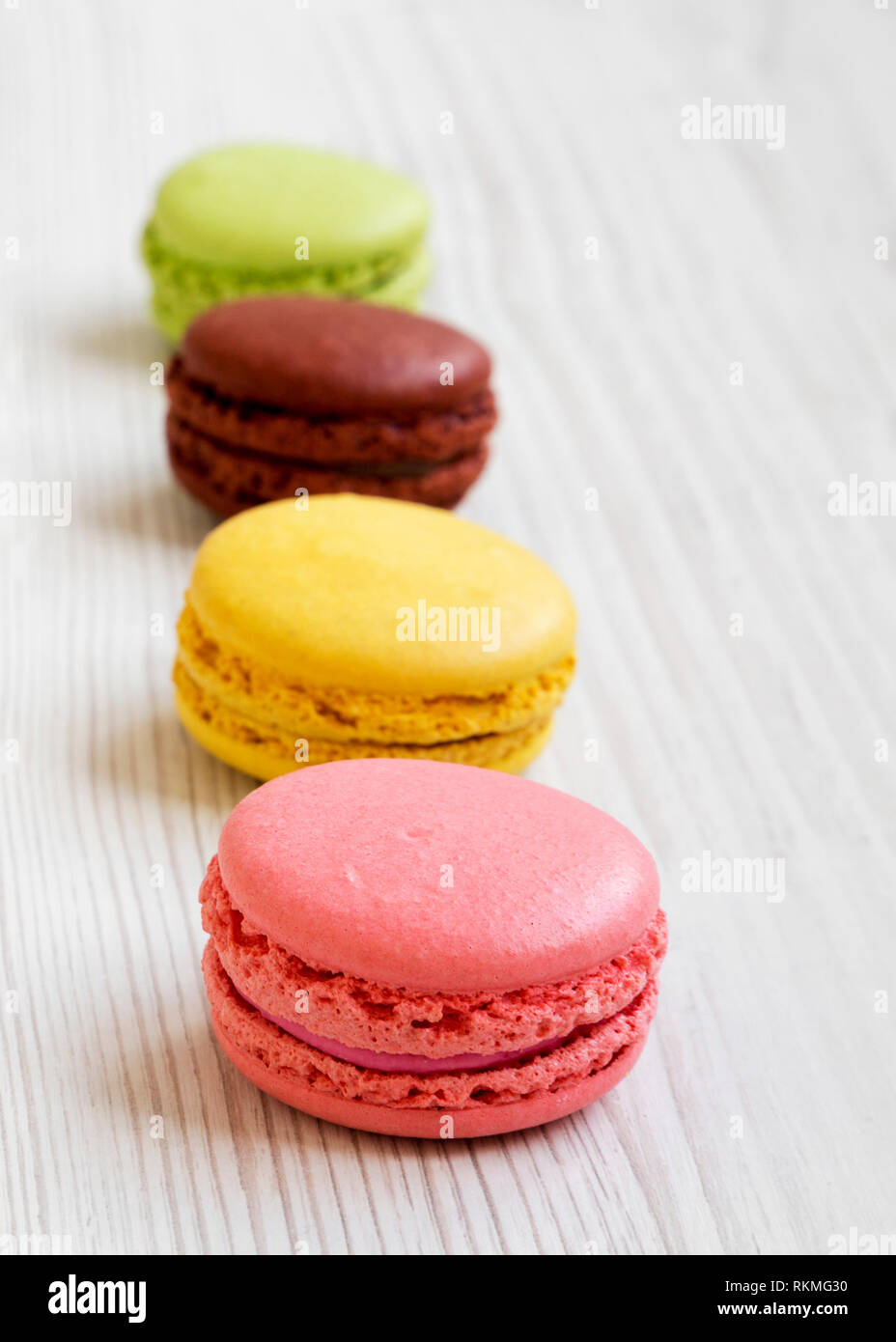 Sweet and colorful macarons on a white wooden background, side view ...
