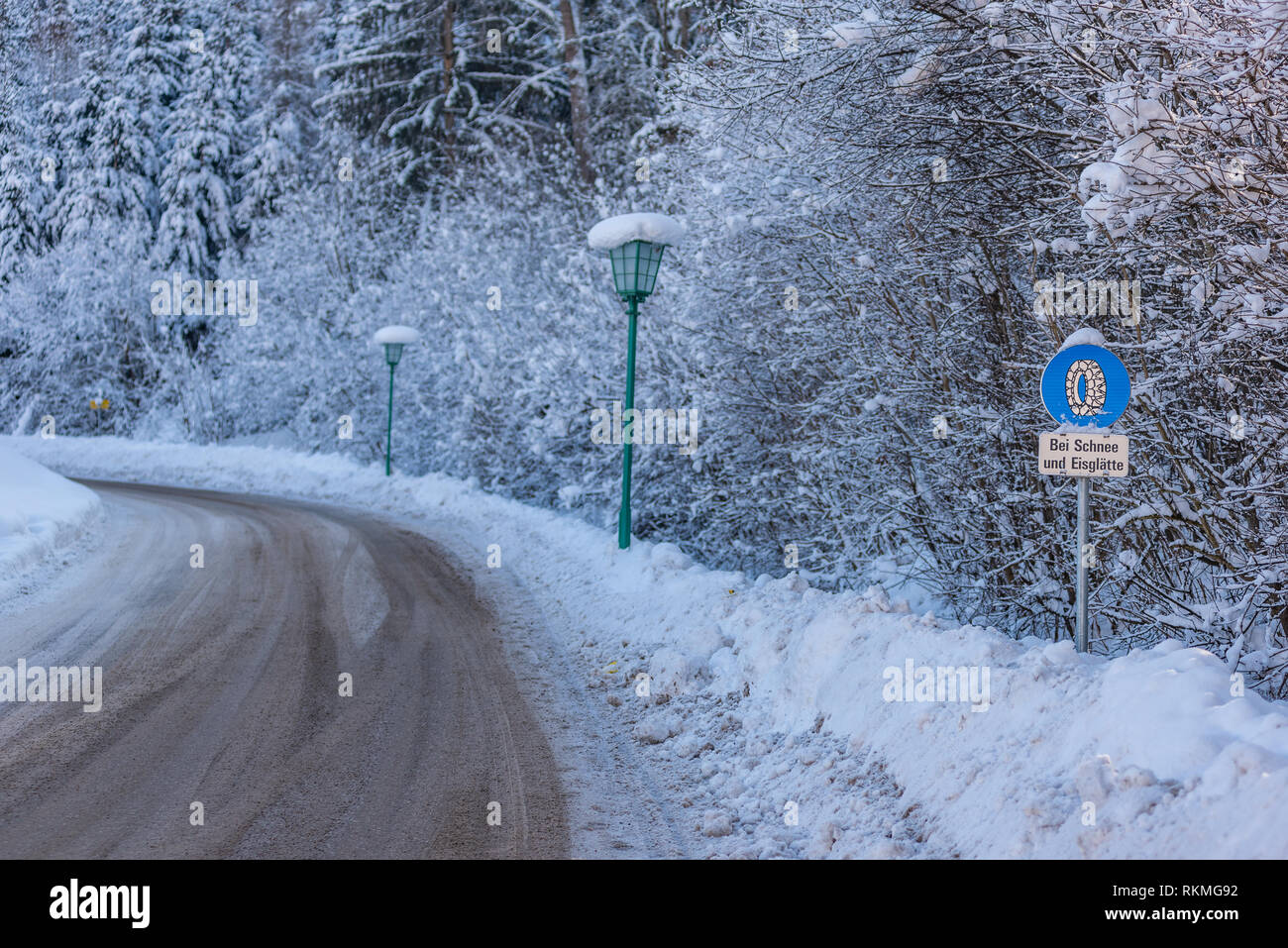 Traffic sign, warning, winter services. Snow covered road, street lamps ...