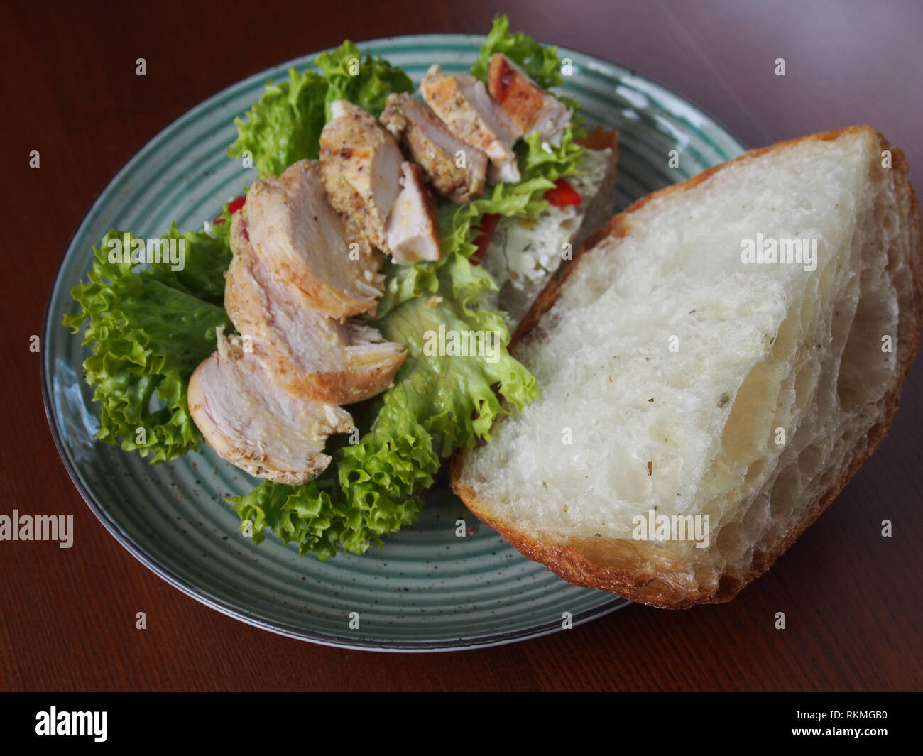 On a large plate lies a sandwich of rustic bread with chicken fillet on ...