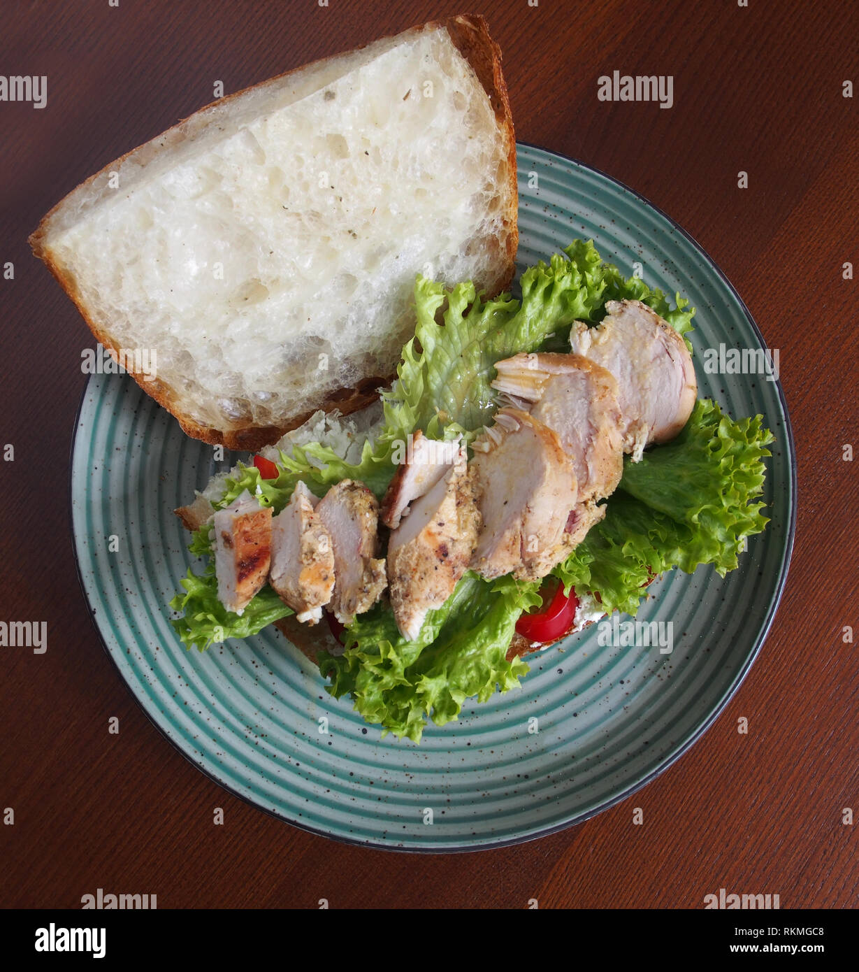 On a large plate lies a sandwich of rustic bread with chicken fillet on ...