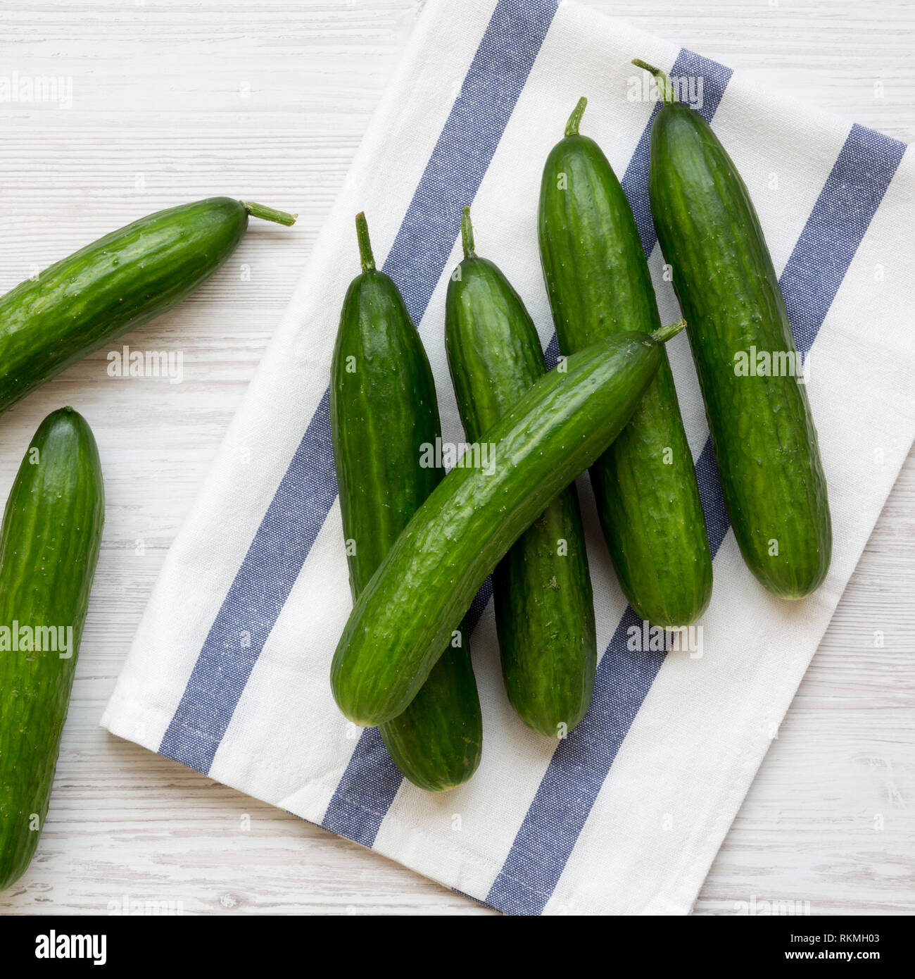 Fresh raw green cucumbers on white wooden table, top view. Flat lay ...
