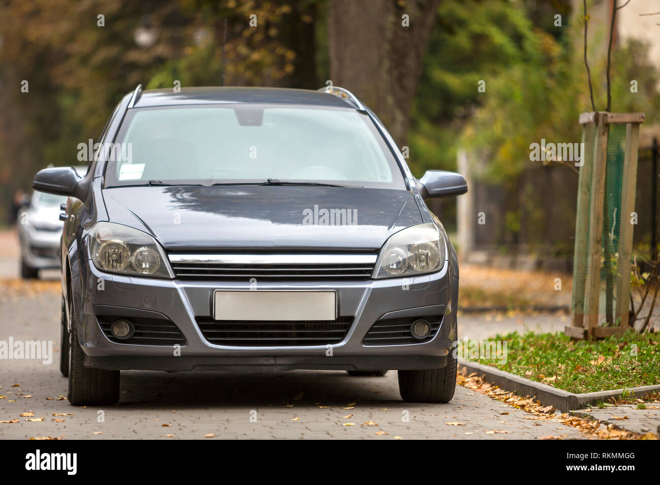 Gray shiny car parked in quiet area on asphalt road on blurred bokeh ...