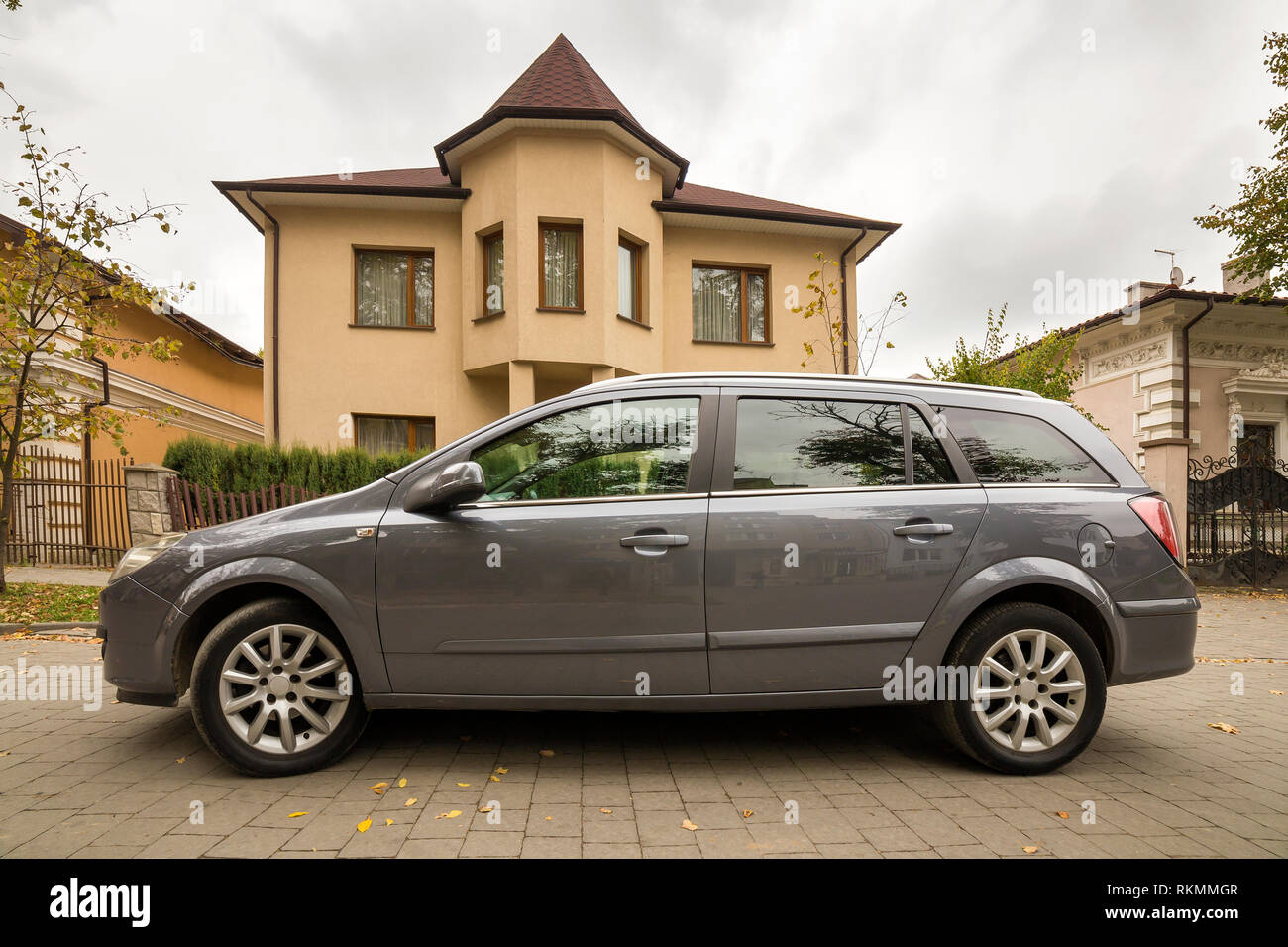 New expensive gray car parked in paved parking lot in front of big two ...