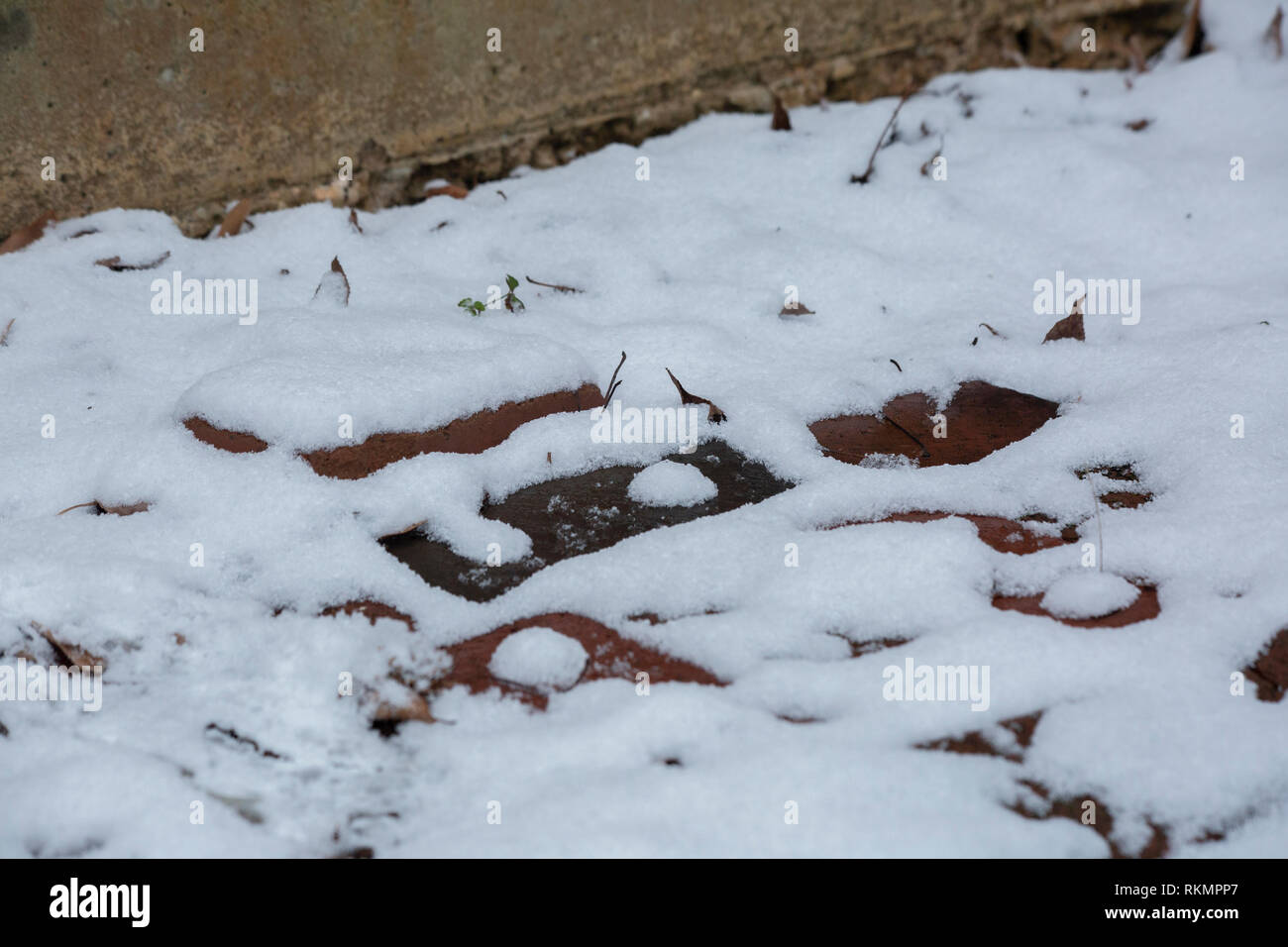 Red bricks peeking out from a light layer of snow Stock Photo - Alamy