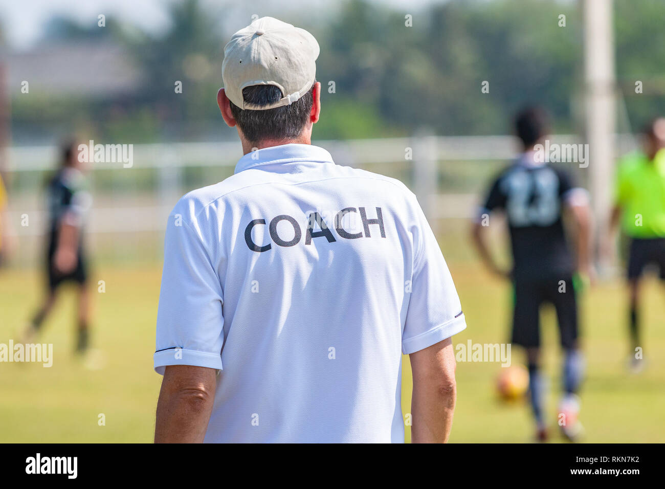 Back of male football coach wearing white COACH shirt at an outdoor ...