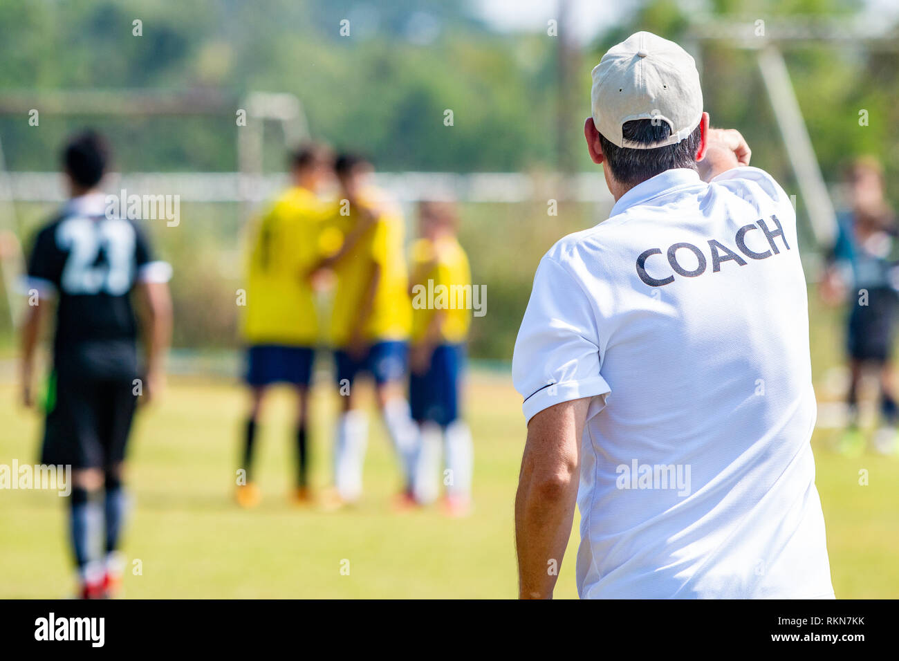 Back of male football coach wearing white COACH shirt at an outdoor ...
