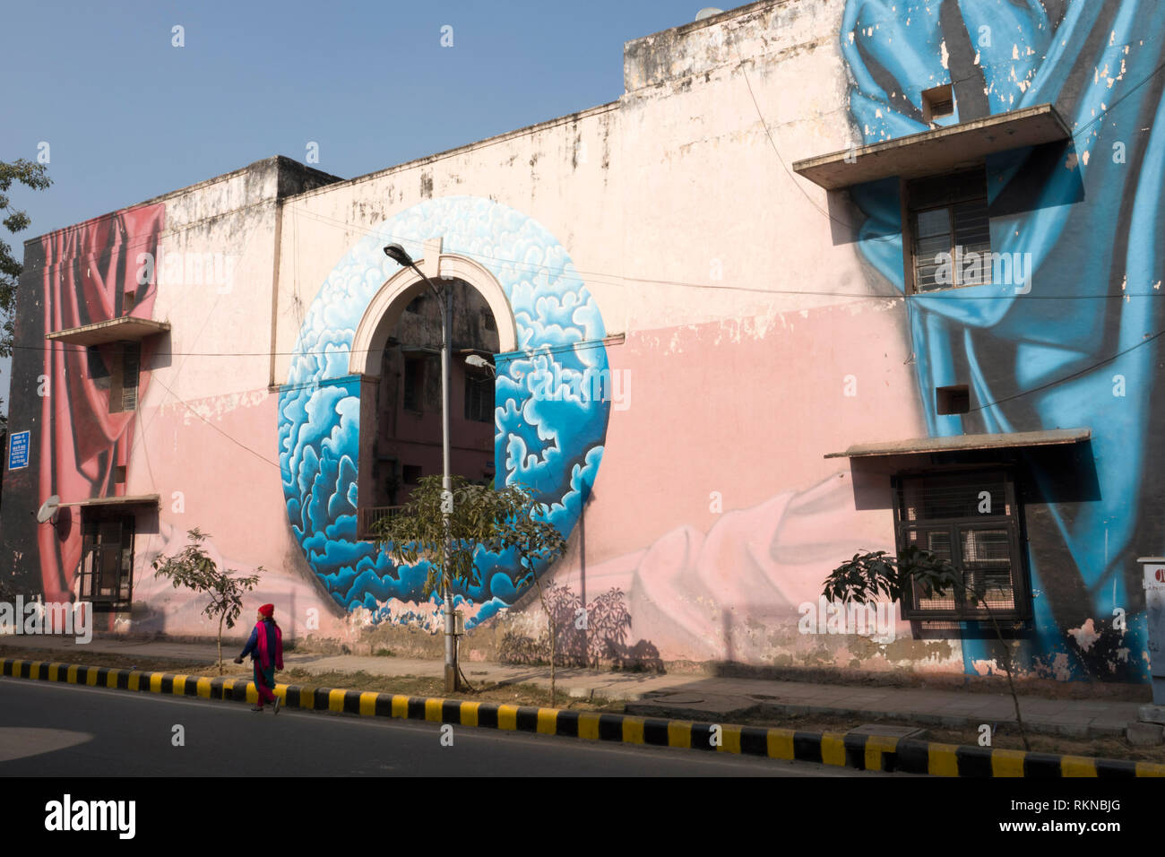 Woman walks past a large mural painted on side of building in Lodhi ...