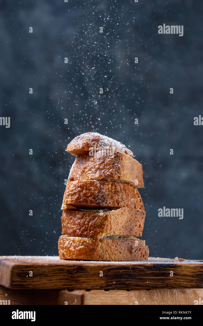 Fresh craft bread sliced on decorative boards with flour sprinkled on ...
