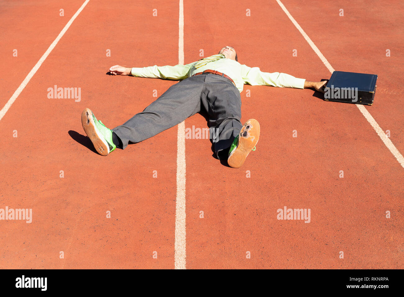 An exhausted business man in gray suit with green shirt and tie, black ...