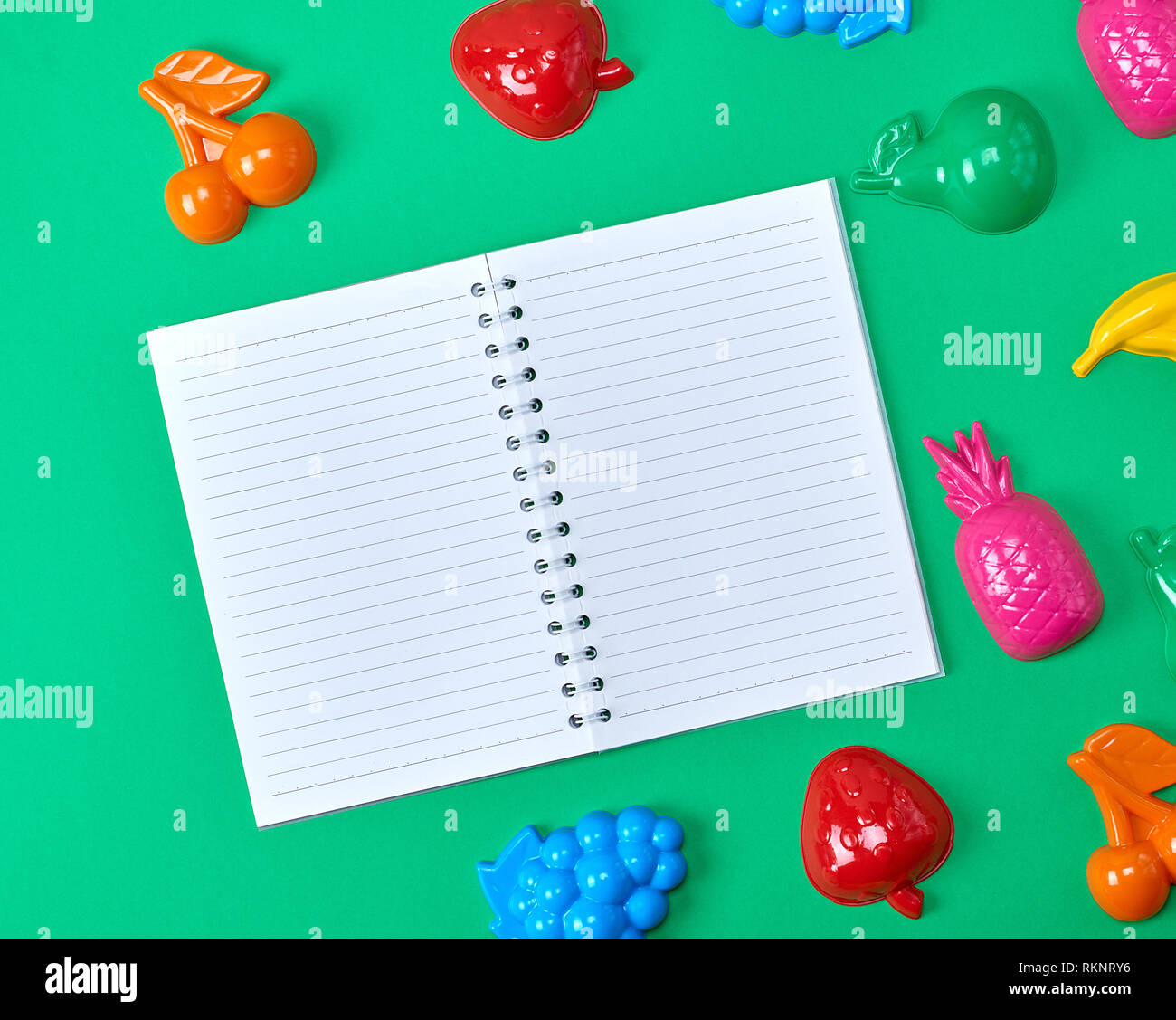 open notebook in line on a green background and children's plastic toys ...