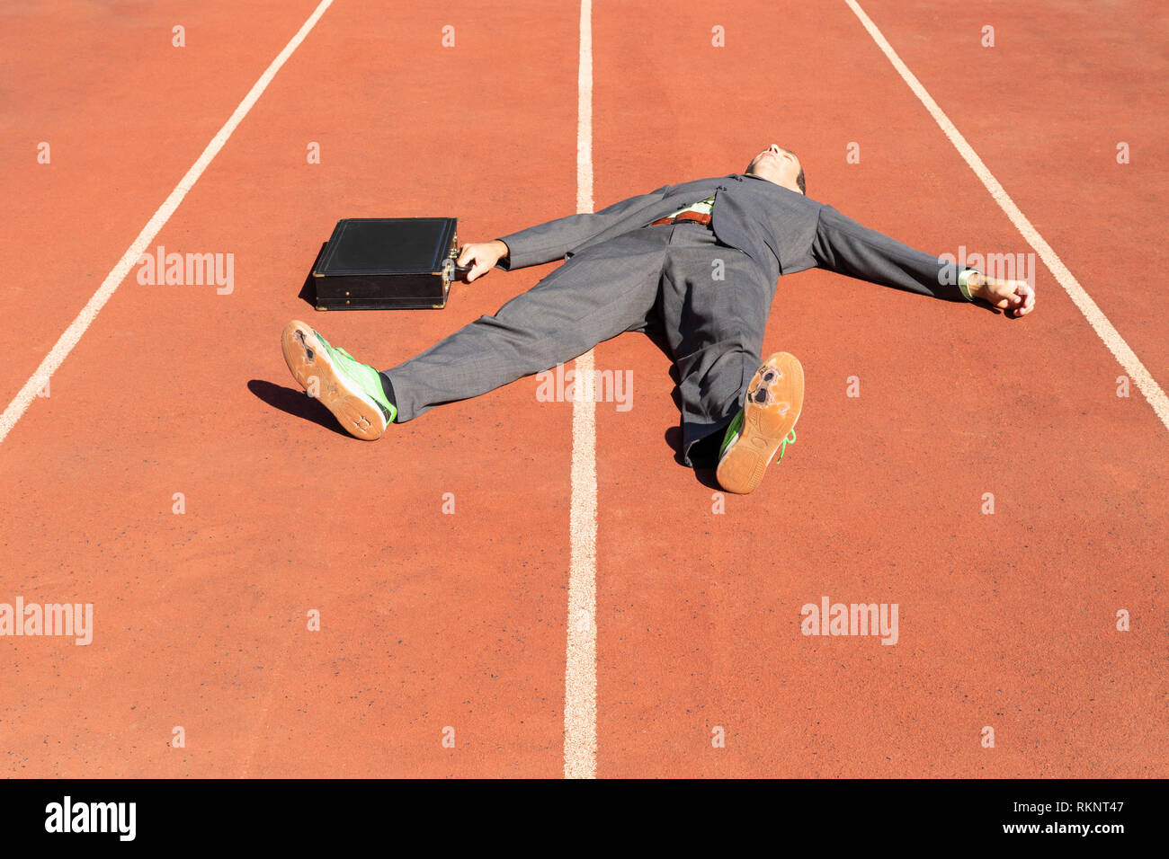 An exhausted business man in gray suit with green shirt and tie, black ...
