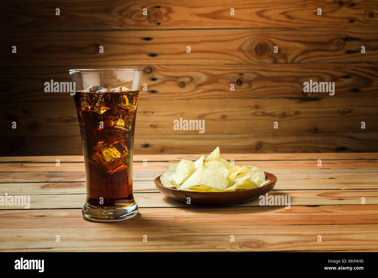 Potato chips with cola on a wooden background Stock Photo - Alamy