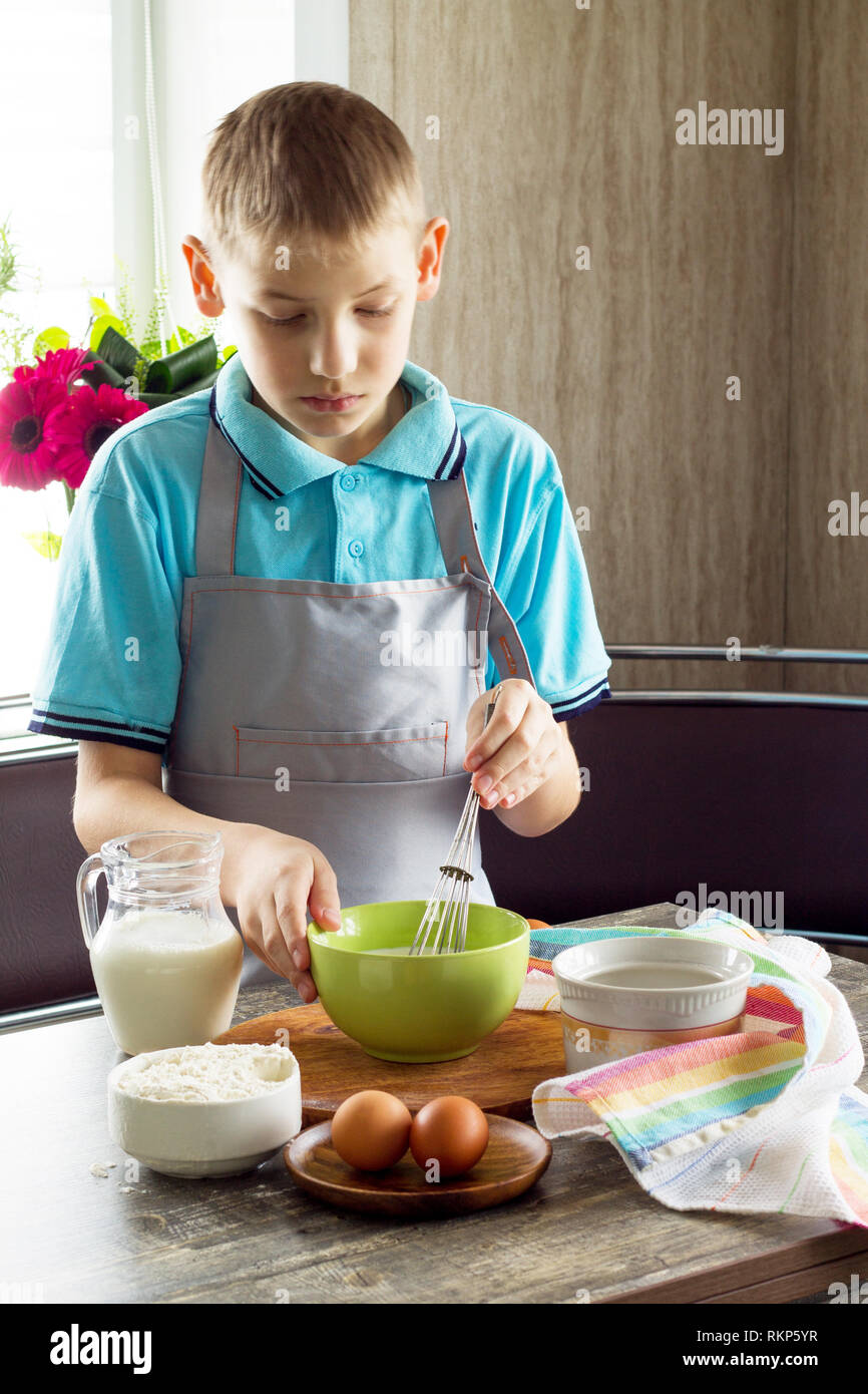 Funny happy chef boy cooking on a kitchen table and cooking dough. Food ...