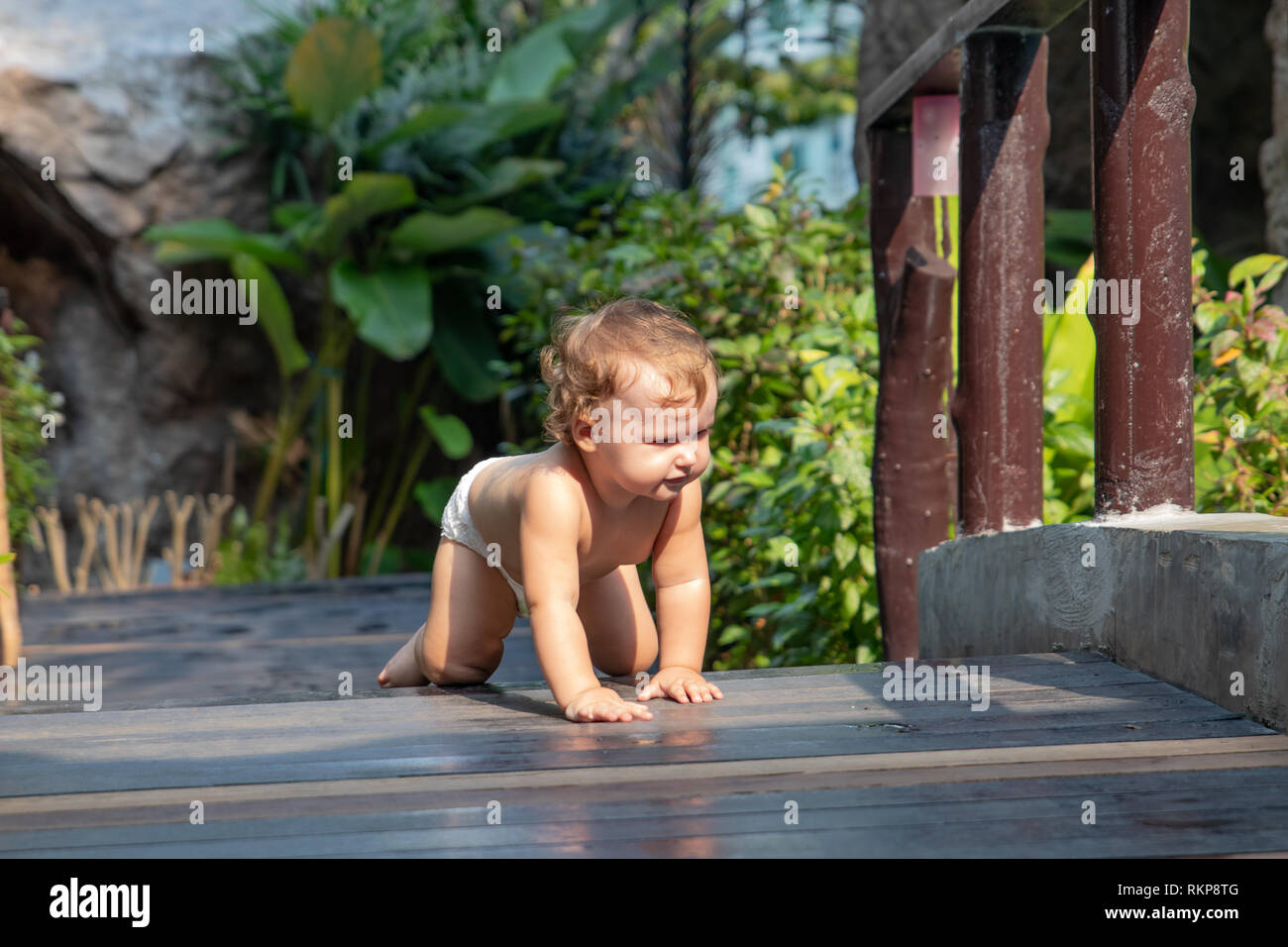child crawls along the dark brown wooden walkway of the bridge at ...