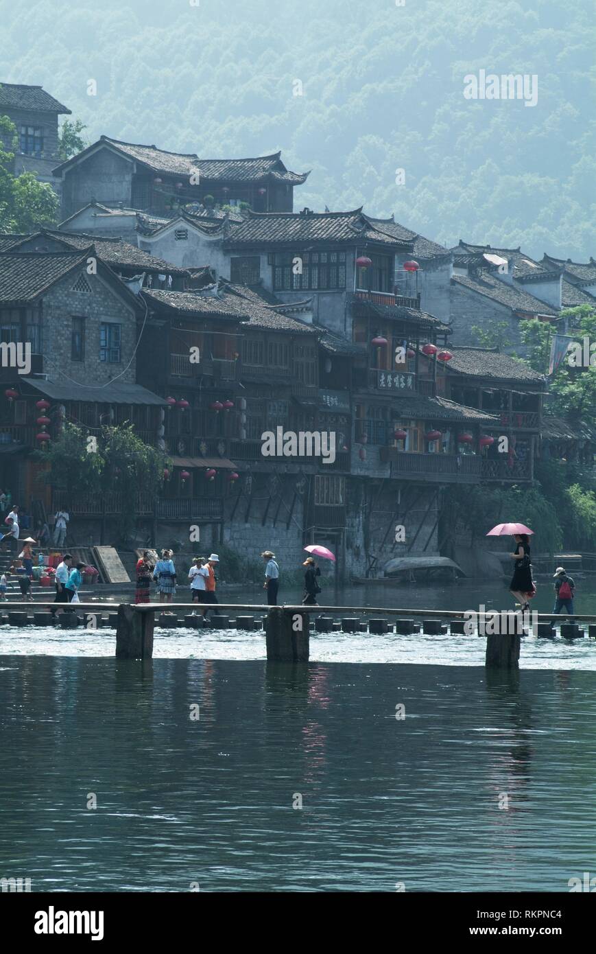 Crossing the Tou Jiang River on stepping stones in the scenic town of ...