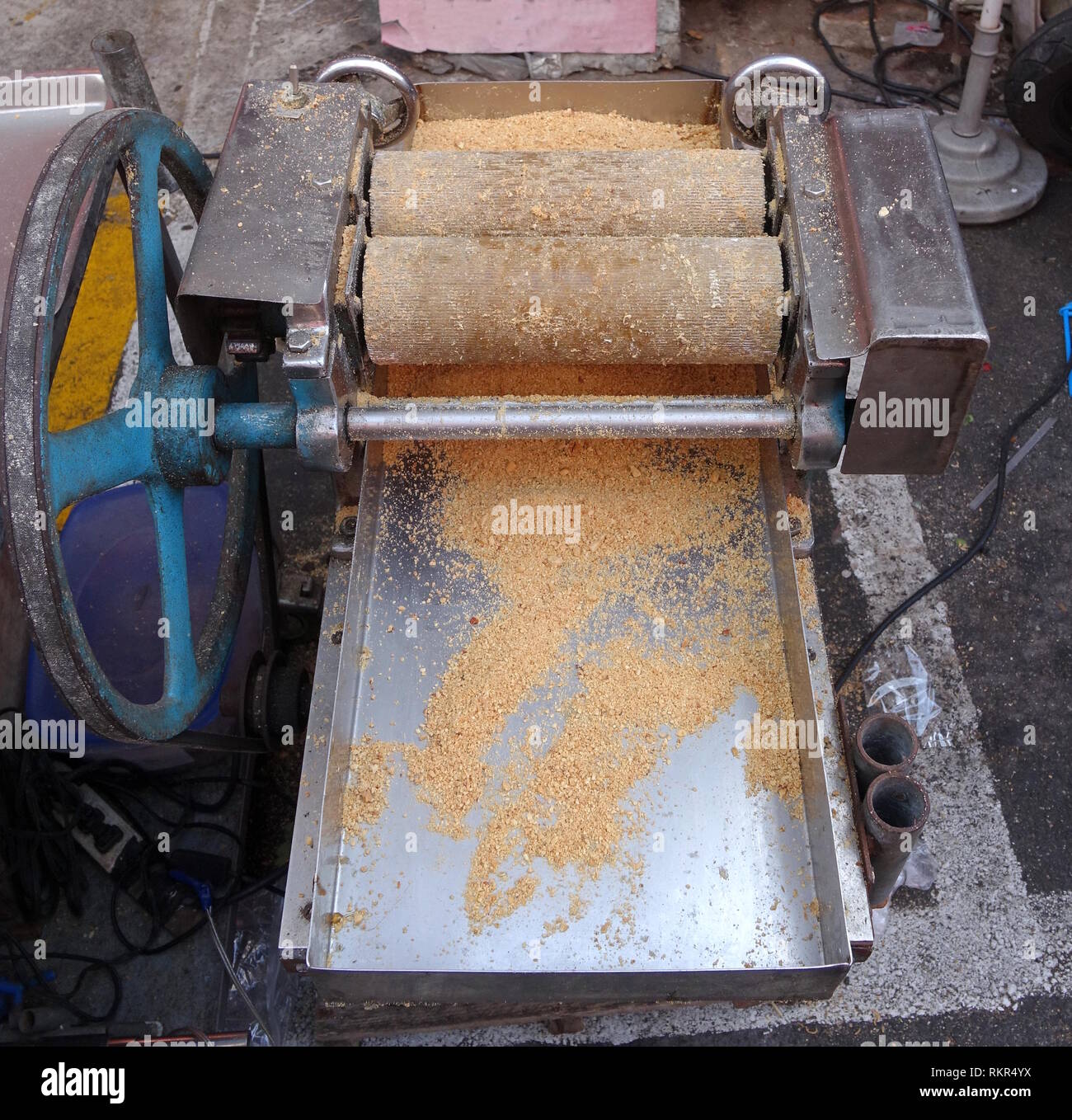 A market stall uses a hand-operated vintage peanut crusher to make ...