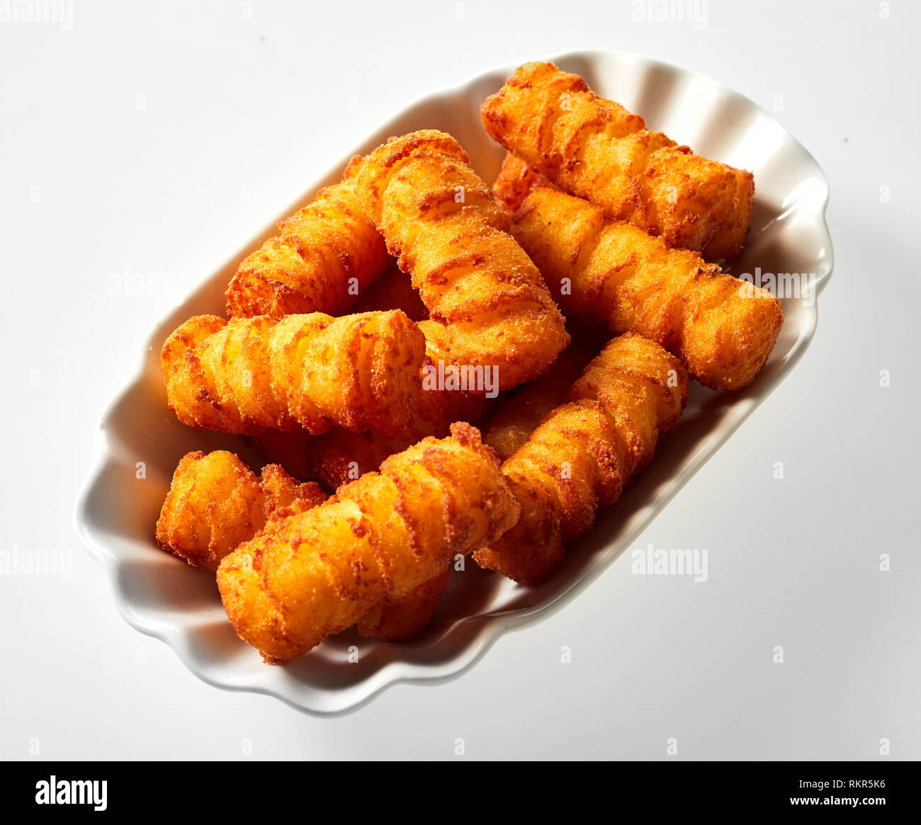 Fluted dish with golden fried potato croquettes fingers with ridged ...