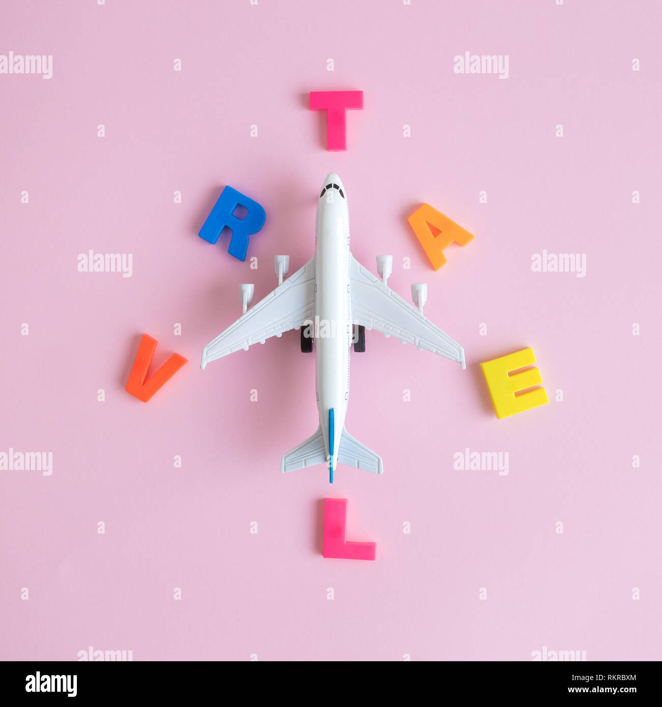 Top view of passenger jet airliner with colorful travel text letters ...