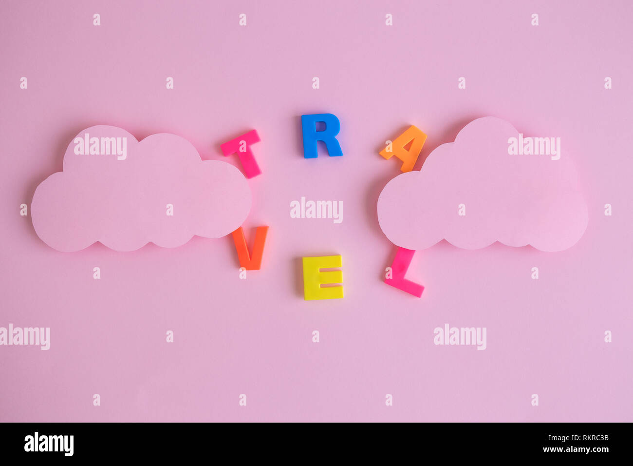 Flat lay of colorful travel text letters and pastel pink clouds minimal ...