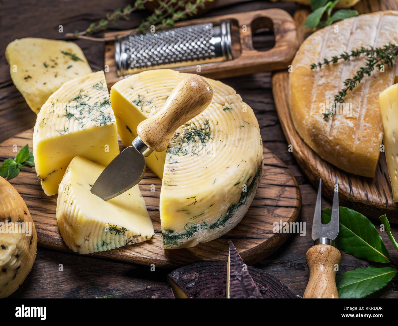 Cheese wheel with herbs and cutlery on the wooden background. Cheese ...