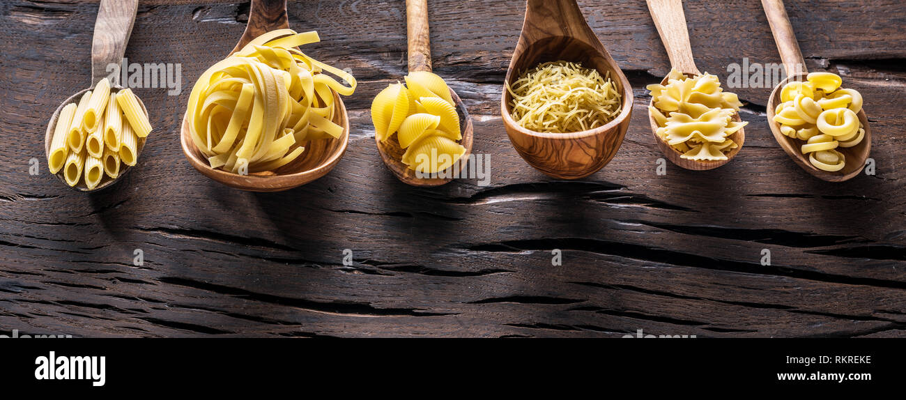 Different pasta types in wooden spoons on the table. Top view Stock ...