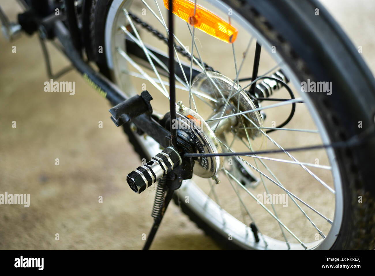 Back wheel of black and orange bycicle with concrete wall design retro ...