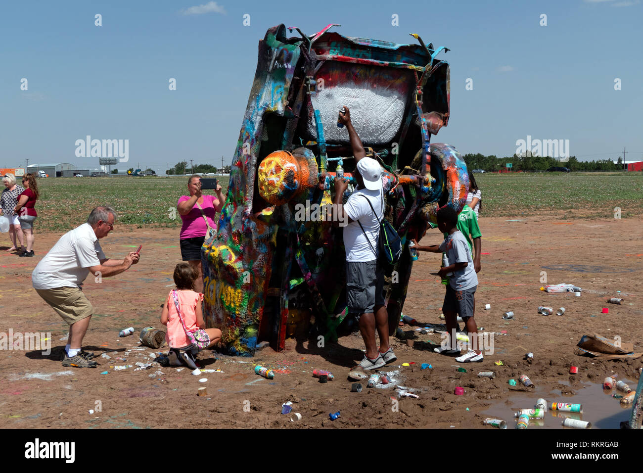 People and tourists spray painting at the Cadillac Ranch, a public art ...