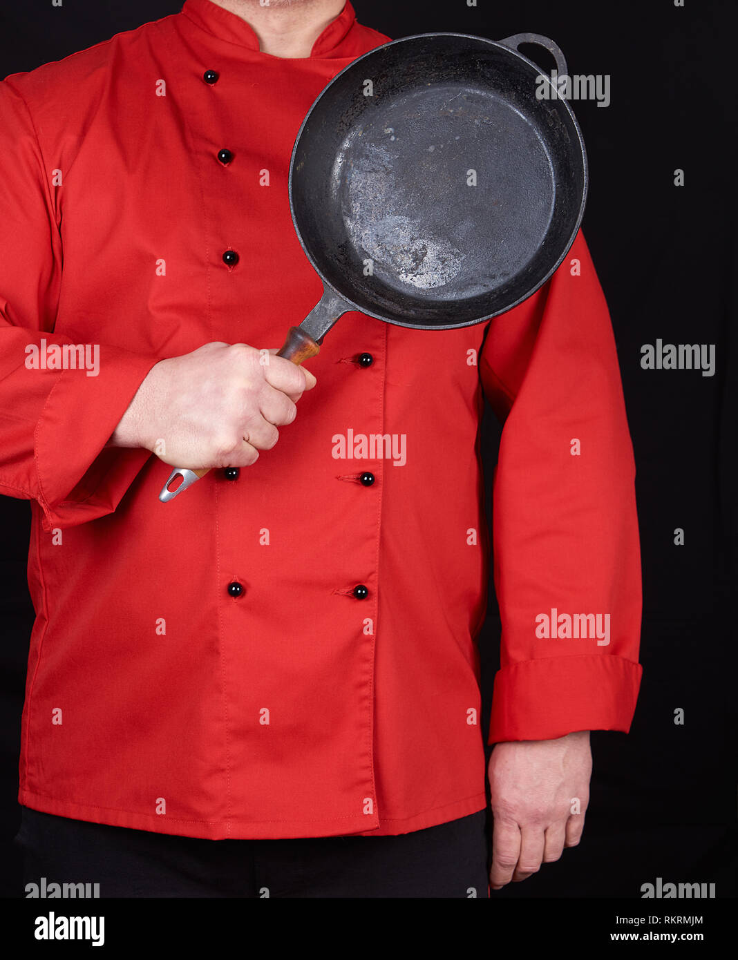 cook in red uniform holding an empty round black frying pan, black ...