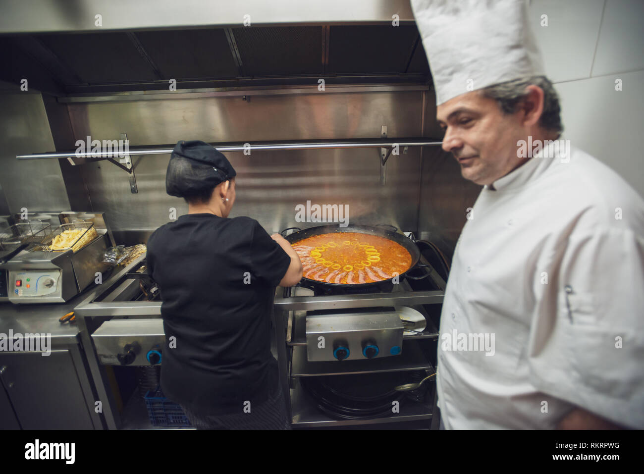 A chef cooking a seafood paella in a restaurant kitchen in Valencia ...