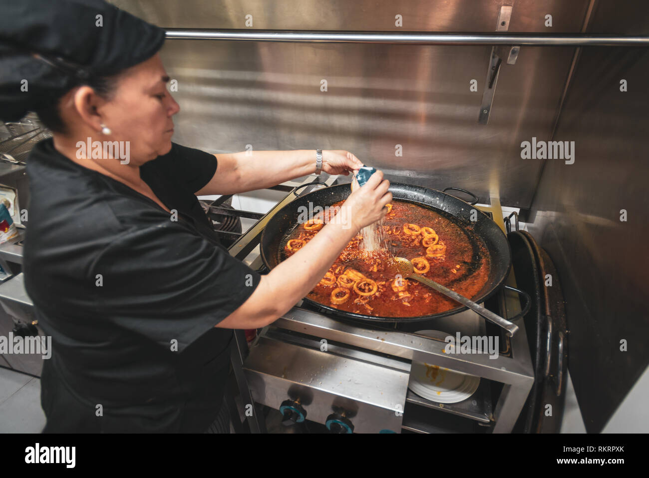 A chef cooking a seafood paella in a restaurant kitchen in Valencia ...