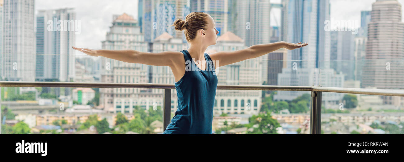 Young woman is practicing yoga in the morning on her balcony with a ...
