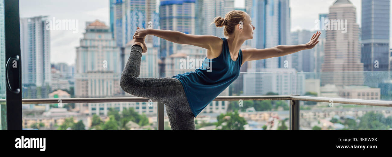 Young woman is practicing yoga in the morning on her balcony with a ...