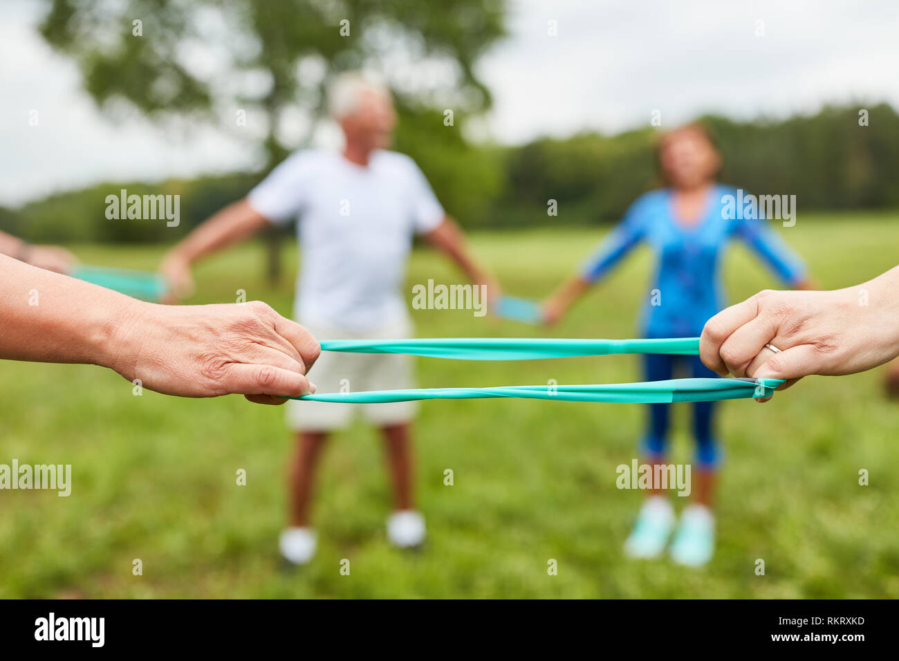 Senior group doing physiotherapy exercise with stretch band in circle ...