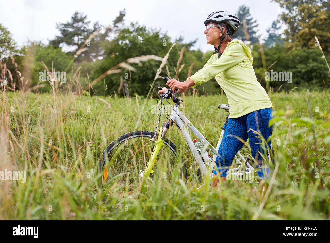 Active senior woman riding a bicycle on a nature bike ride Stock Photo ...