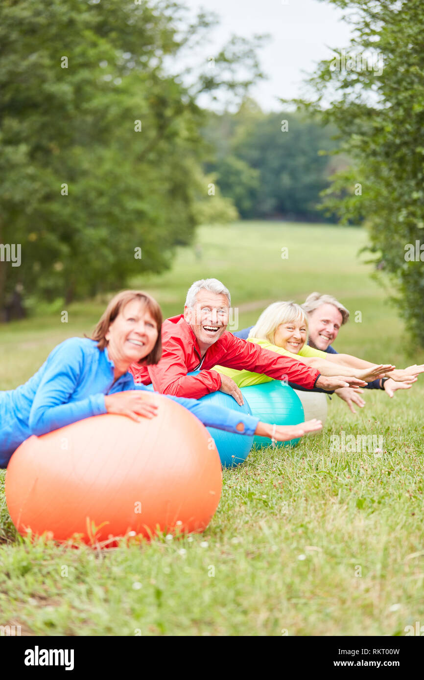 Group of seniors having fun doing an exercise ball exercise in rehab ...