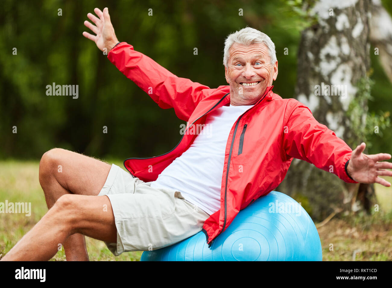 Vital senior man is kidding around with gym ball in pilates class in ...