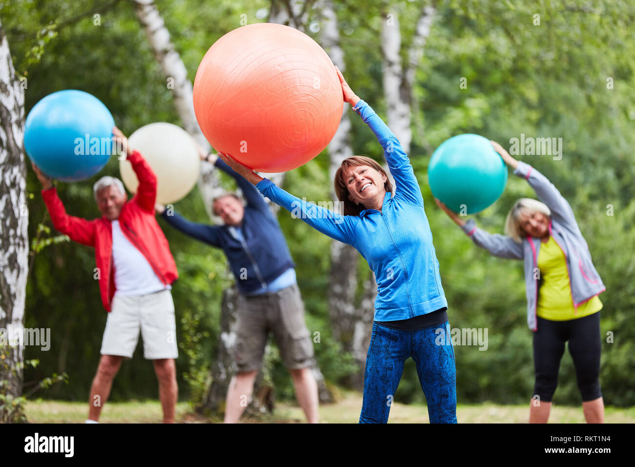 Active seniors group with exercise ball doing a back exercise together ...