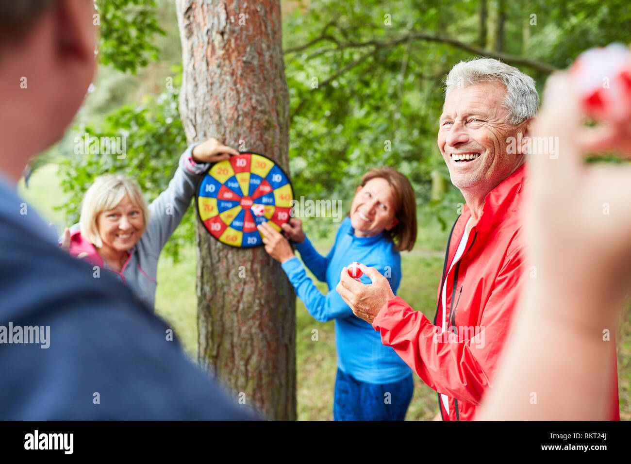 Group of seniors having fun while playing darts together in free time ...