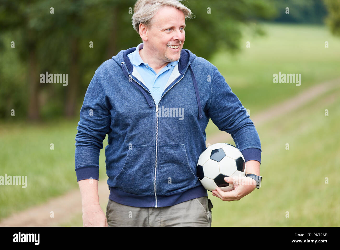 Mature man as a coach with a football in nature in his spare time Stock ...