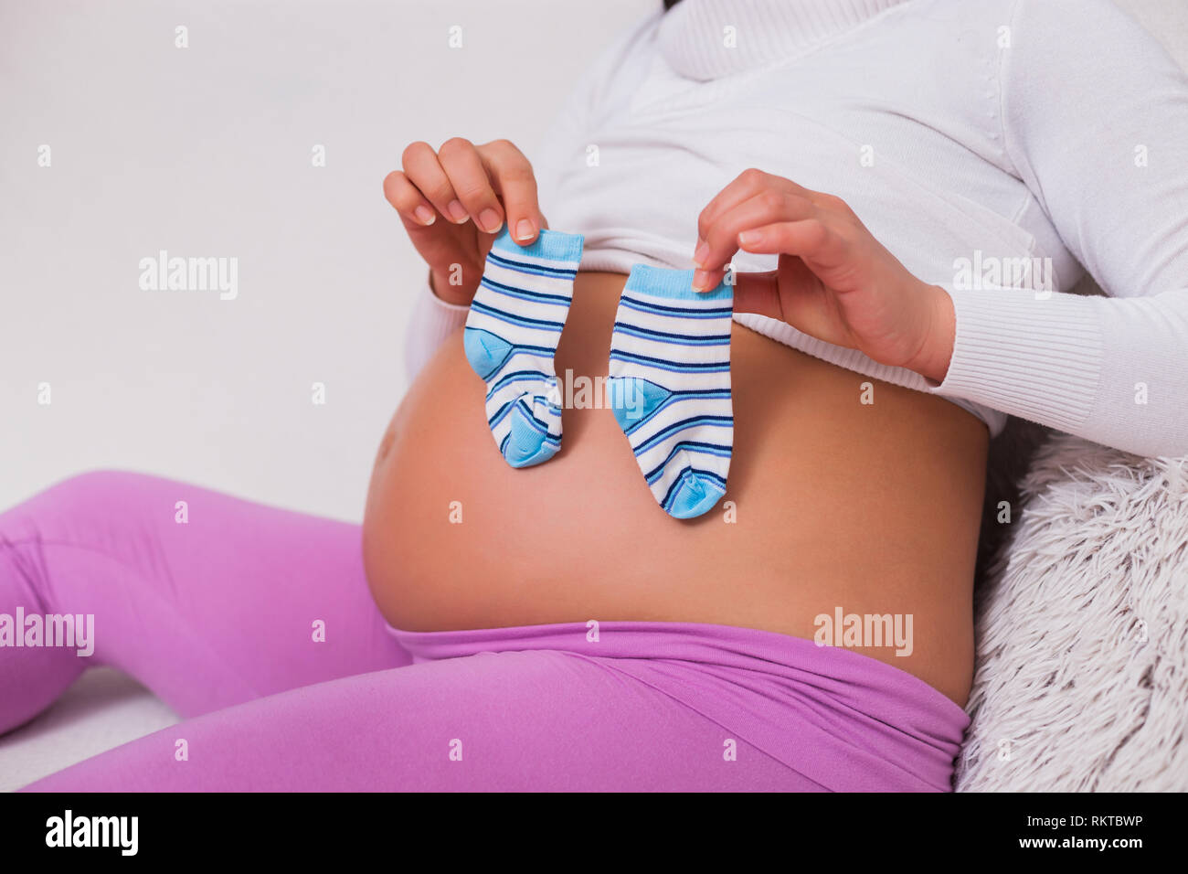 Pregnant woman holding socks for baby Stock Photo - Alamy