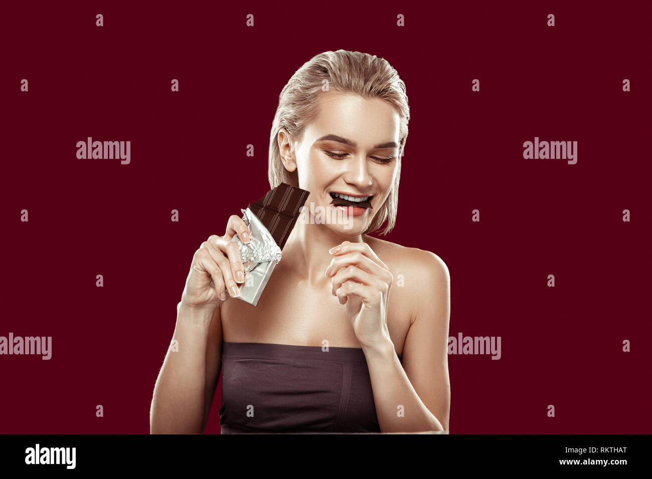 Slim appealing model feeling cheerful while eating chocolate Stock ...
