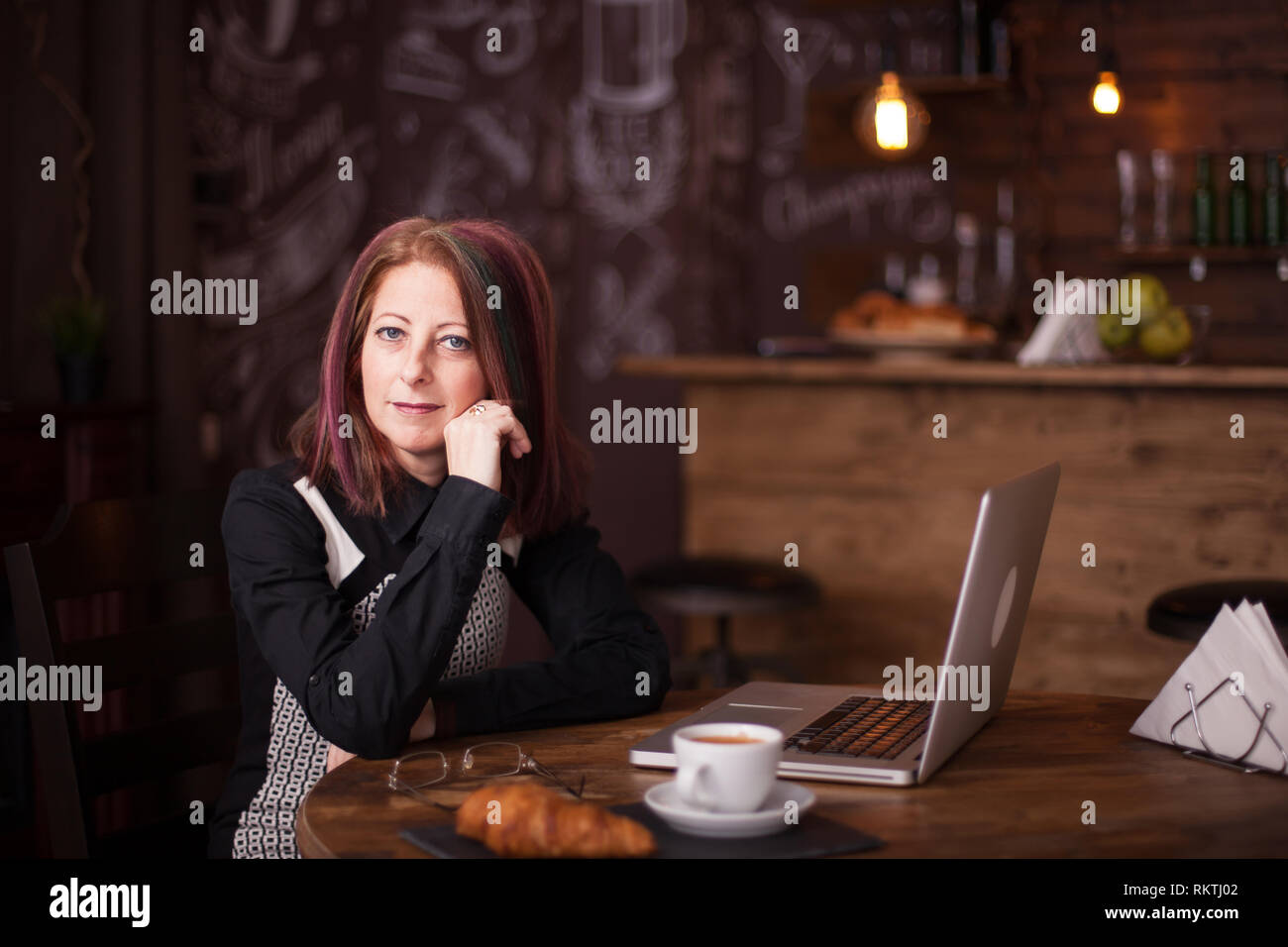 Potrait of adult woman using her laptop in restaurant. Relaxing in pub ...