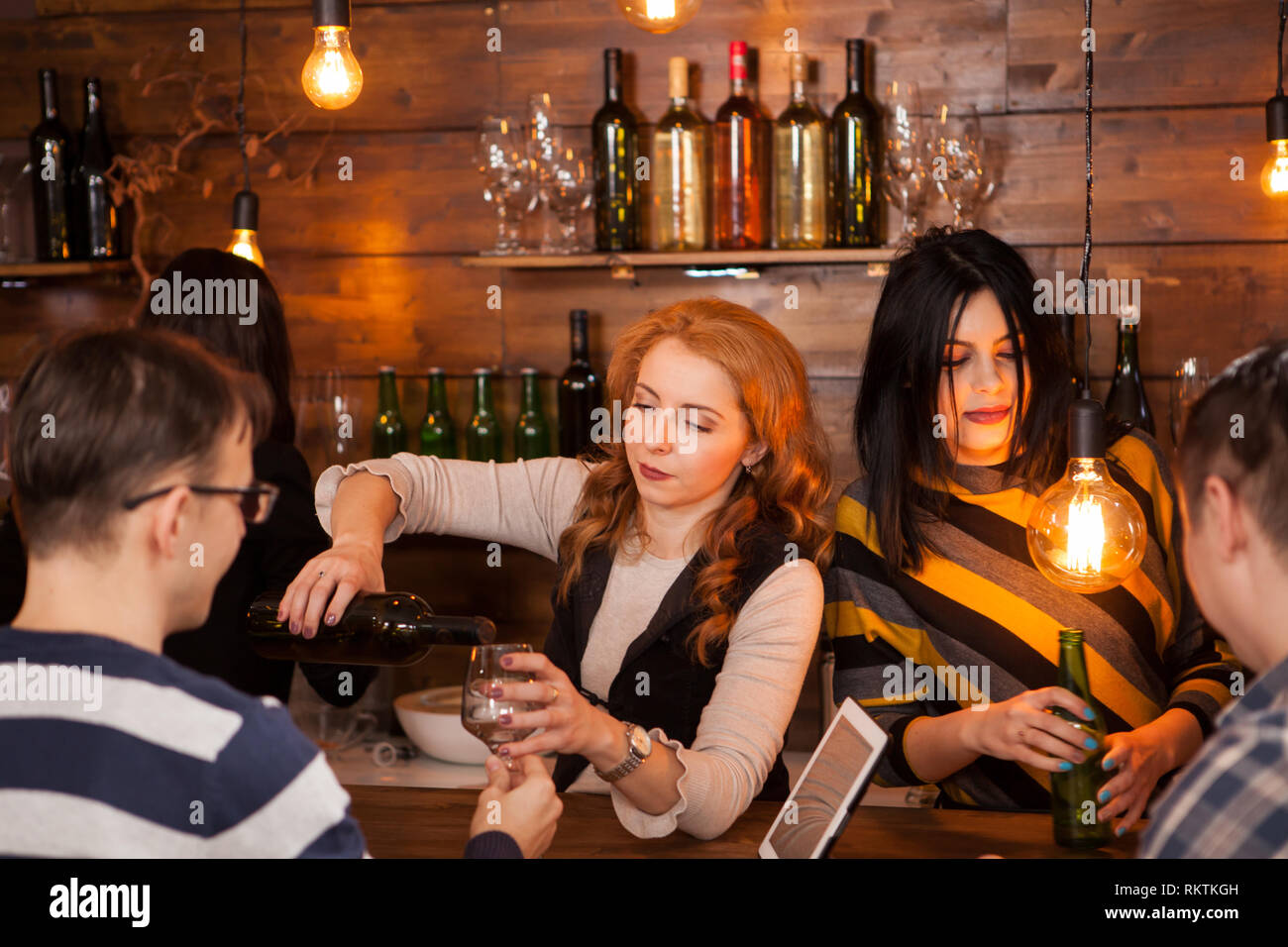 Happy friends interacting at bar counter in a pub. Hipster pub Stock ...