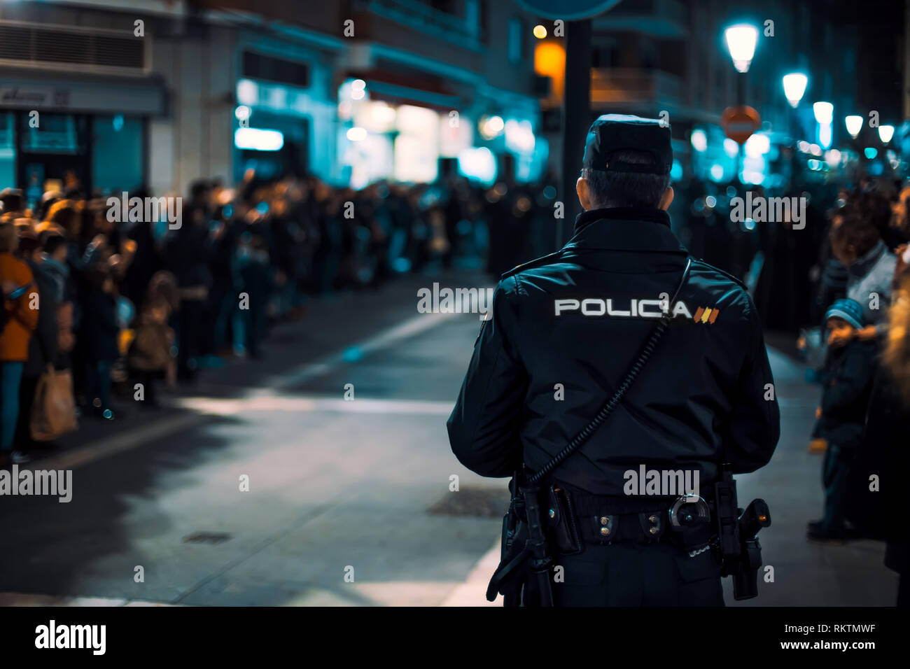 Rear view of Police officer watching during crowded religious event ...